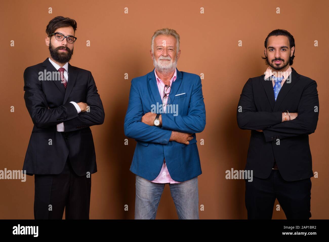 Three multi ethnic bearded businessmen together against brown ...