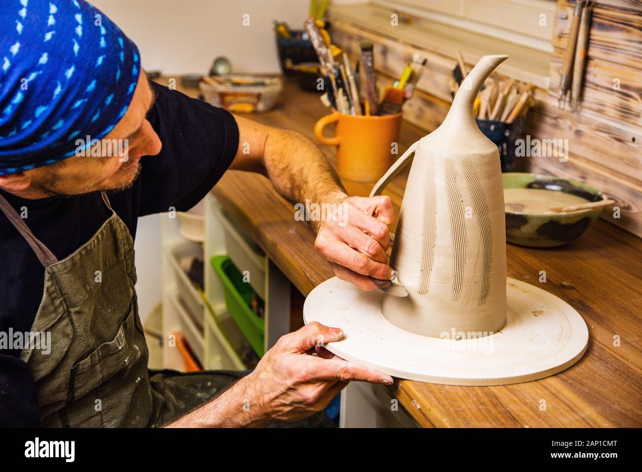 Male master potter working on potter's wheel with raw clay with hands ...
