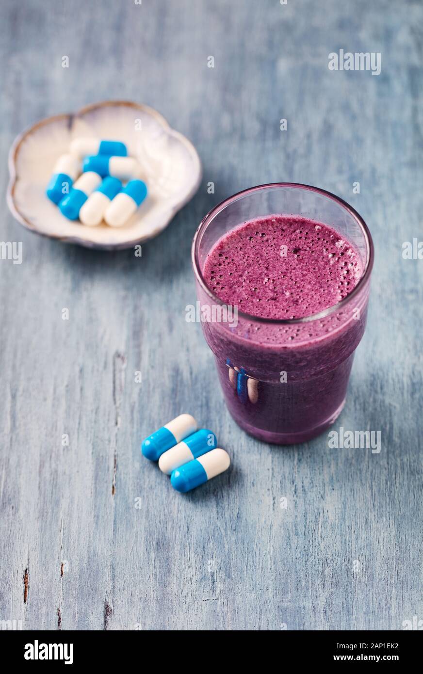 Glass of Protein Shake with milk and blueberries and Creatine capsules ...