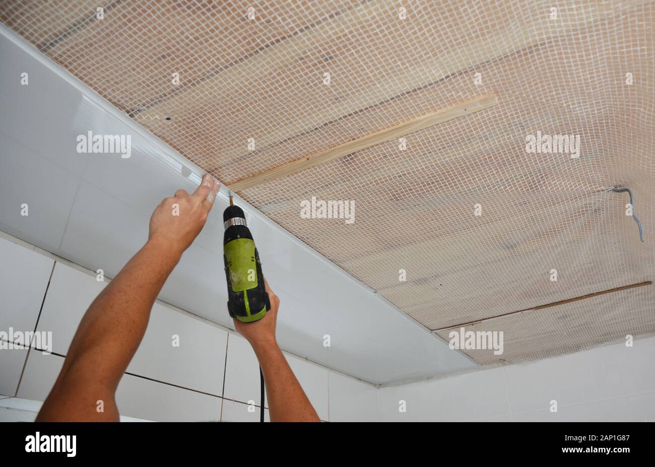 Contractor installing white PVC Ceiling Boards with screw gun in the ...
