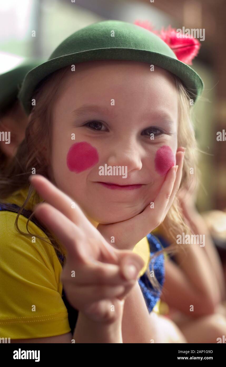 Little girl dressed in costume as a clown painted face wearing a green ...