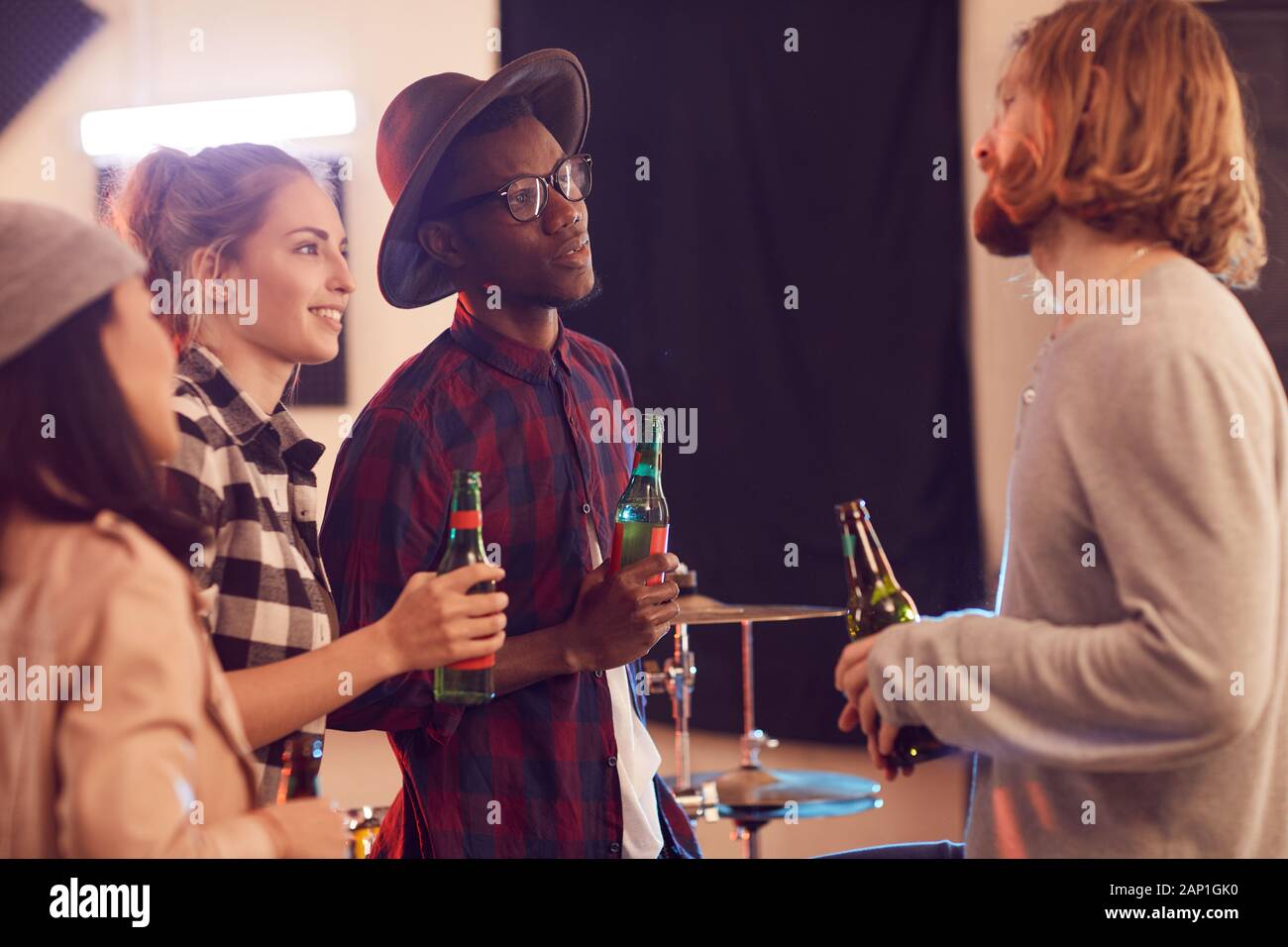 Multi-ethnic group of young people drinking beer and chatting while ...