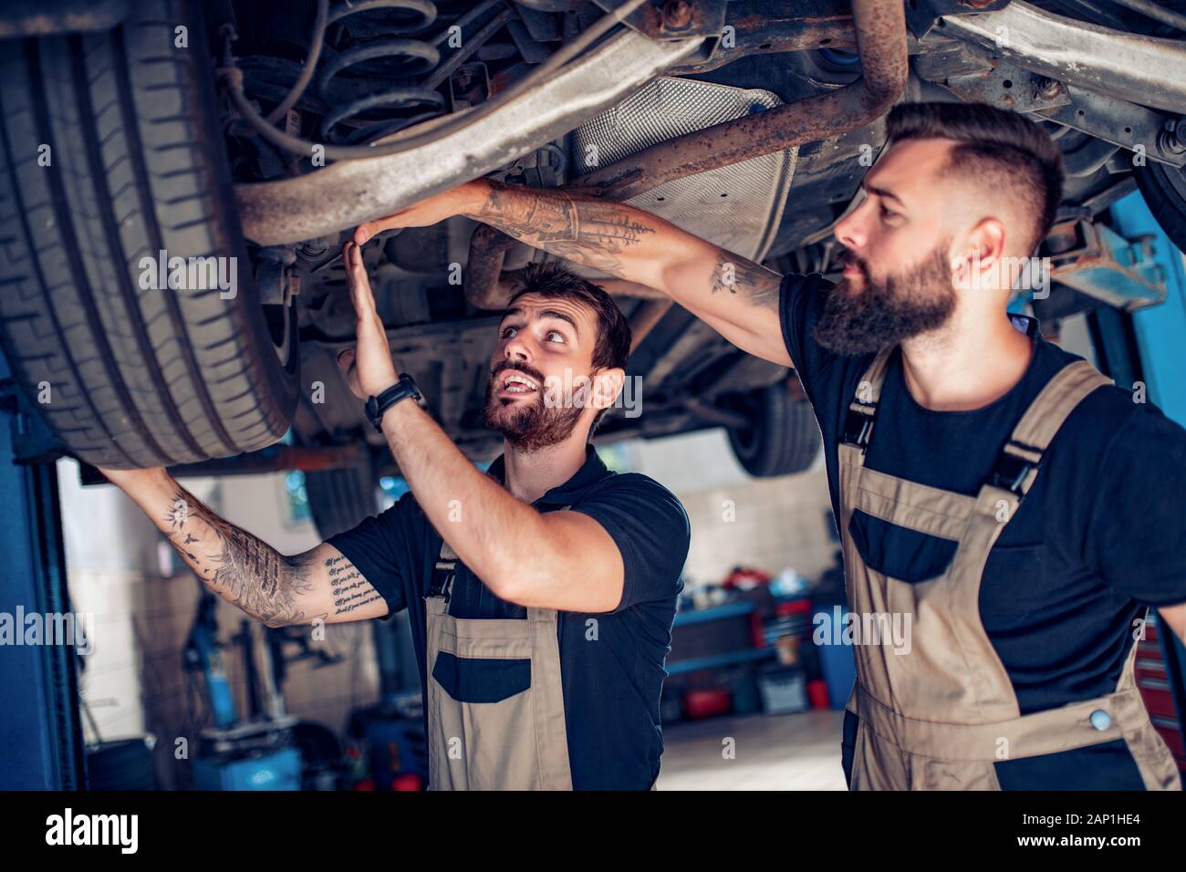 Two mechanics repairing car in service center. Workshop for automobile ...