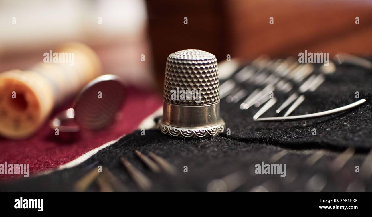 finger thimble and a black needle-felt book. spool of thread and ...