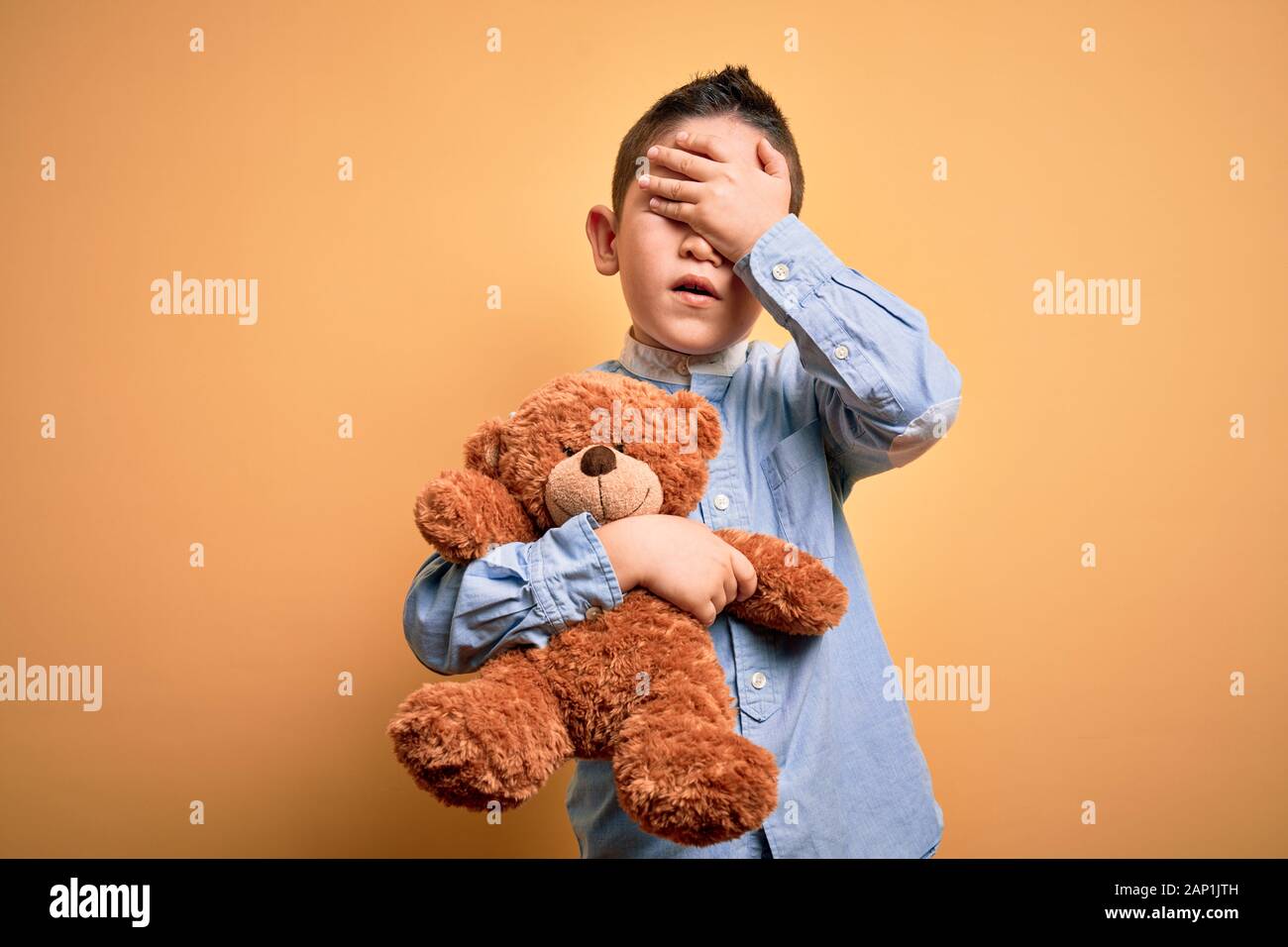 Young little boy kid hugging teddy bear stuffed animal over yellow ...