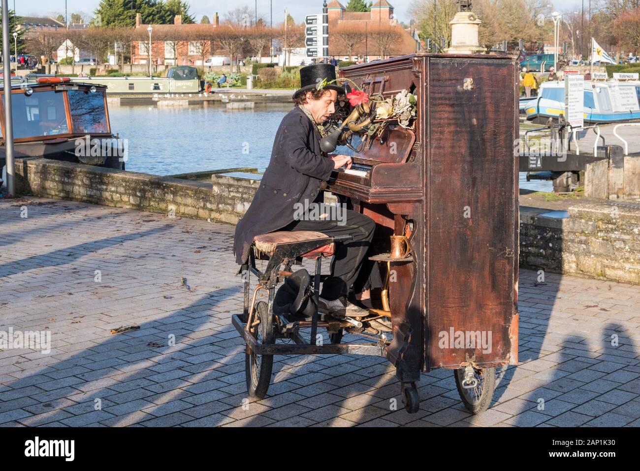 Street musician or busker playing a piano mounted on a bicycle and ...
