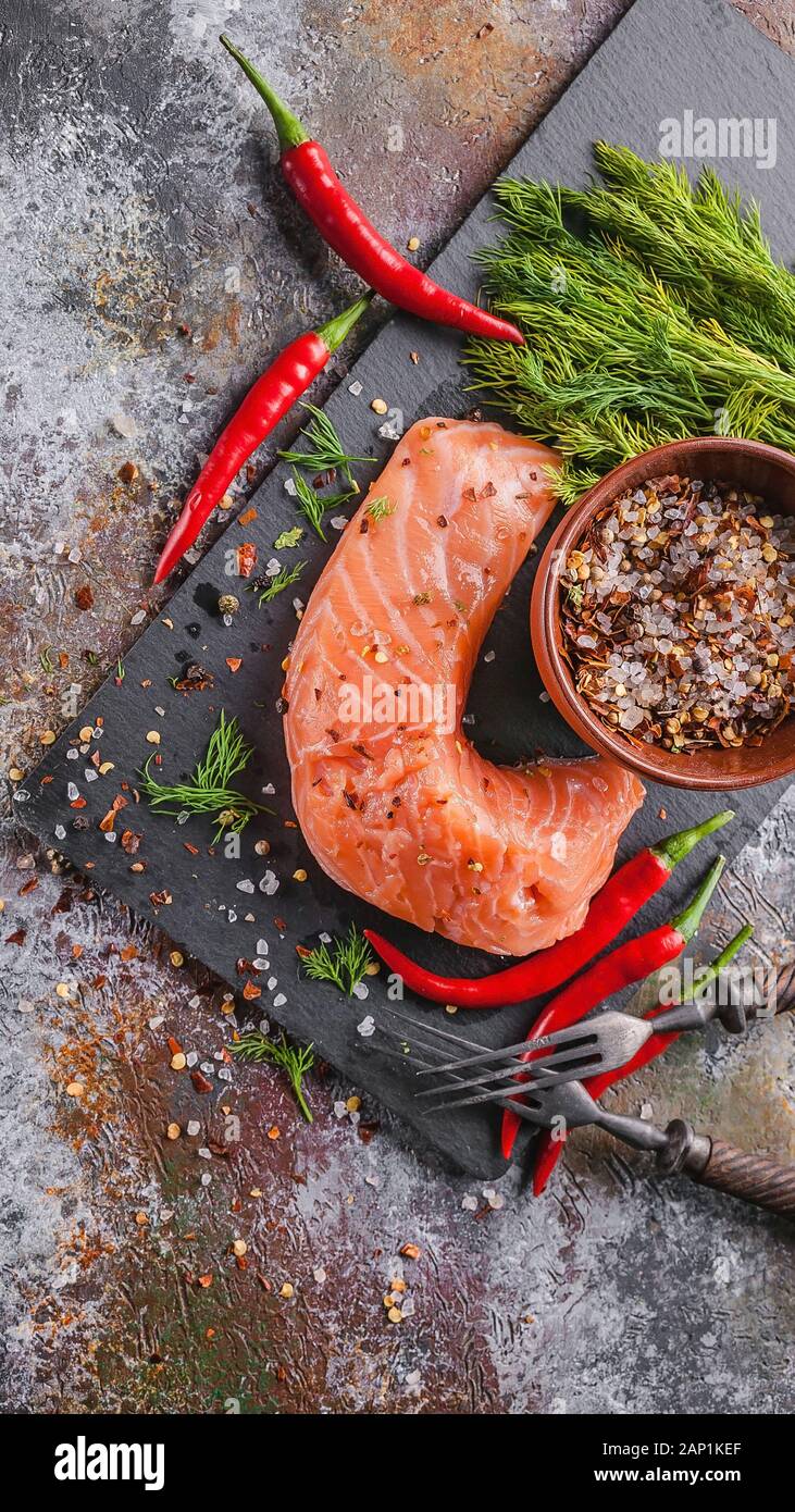 Vertical food banner. Salmon on a ceramic black cutting board. Spices ...
