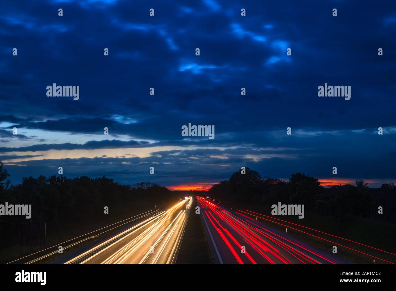 Dramatic evening sky over highway or motorway with car light trails at ...