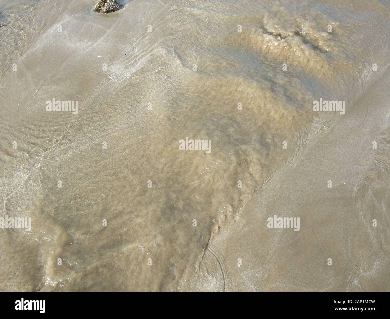 Water flowing over sand forming pattern Stock Photo - Alamy