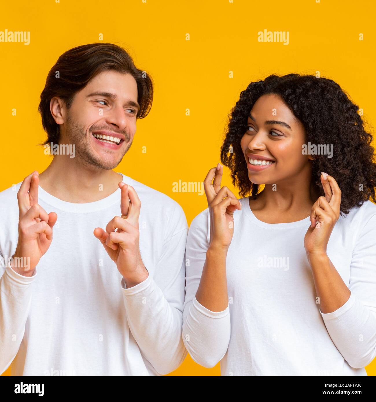 Romantic multiracial couple crossing fingers, making wish together ...