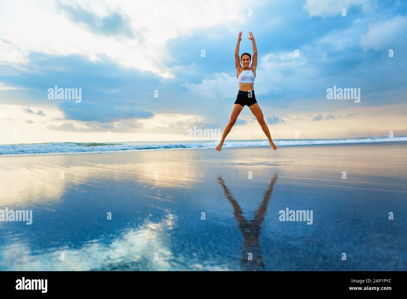 Young woman doing jumping jack or star jumps exercise to burn fat, keep ...