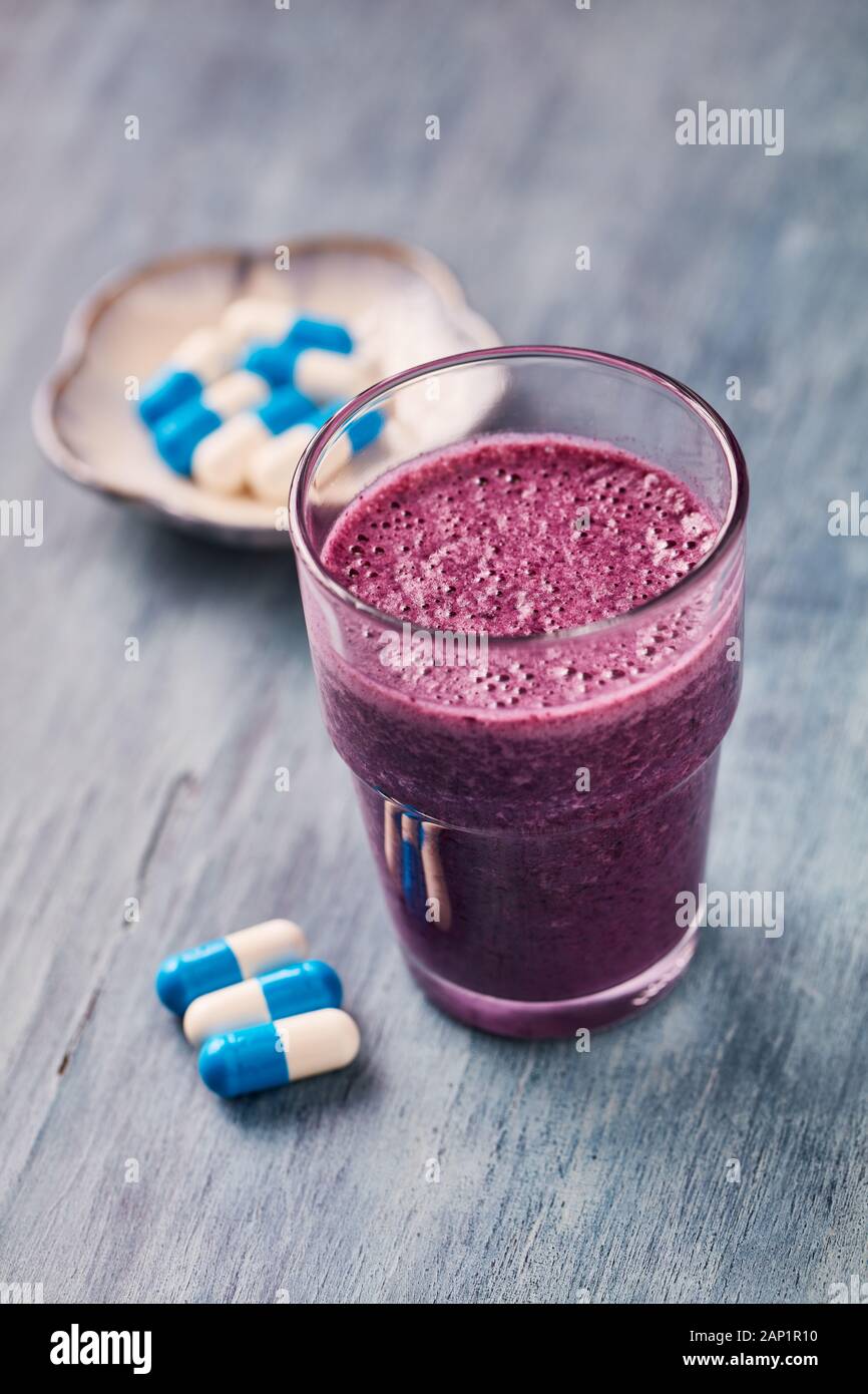 Glass of Protein Shake with milk and blueberries and Creatine capsules ...