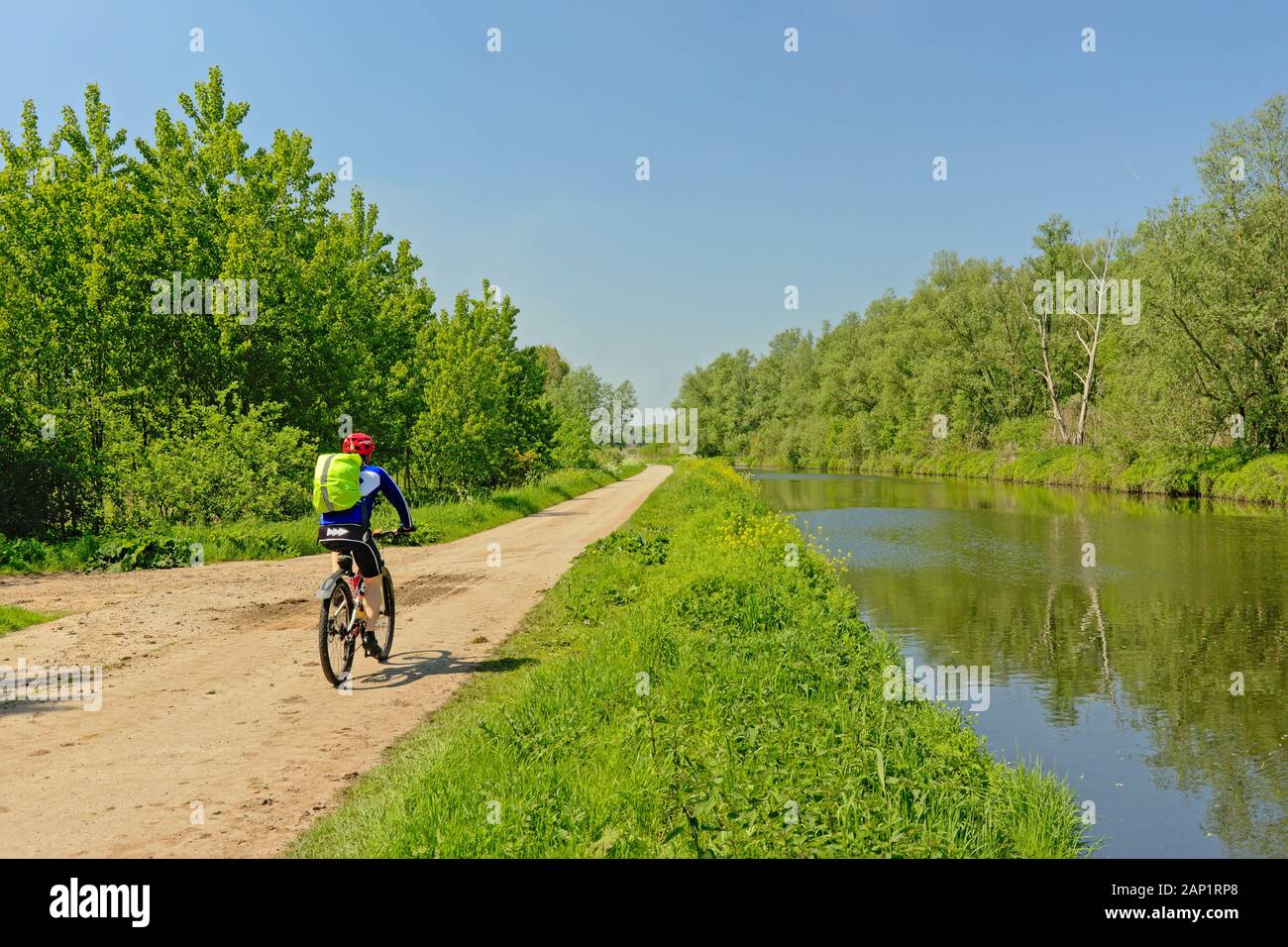 Cylist on a pathlush green borders of the canal `de Moer` on a sunny ...