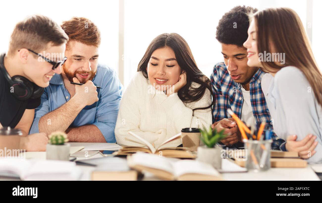 Happy group of students reding book in library Stock Photo - Alamy