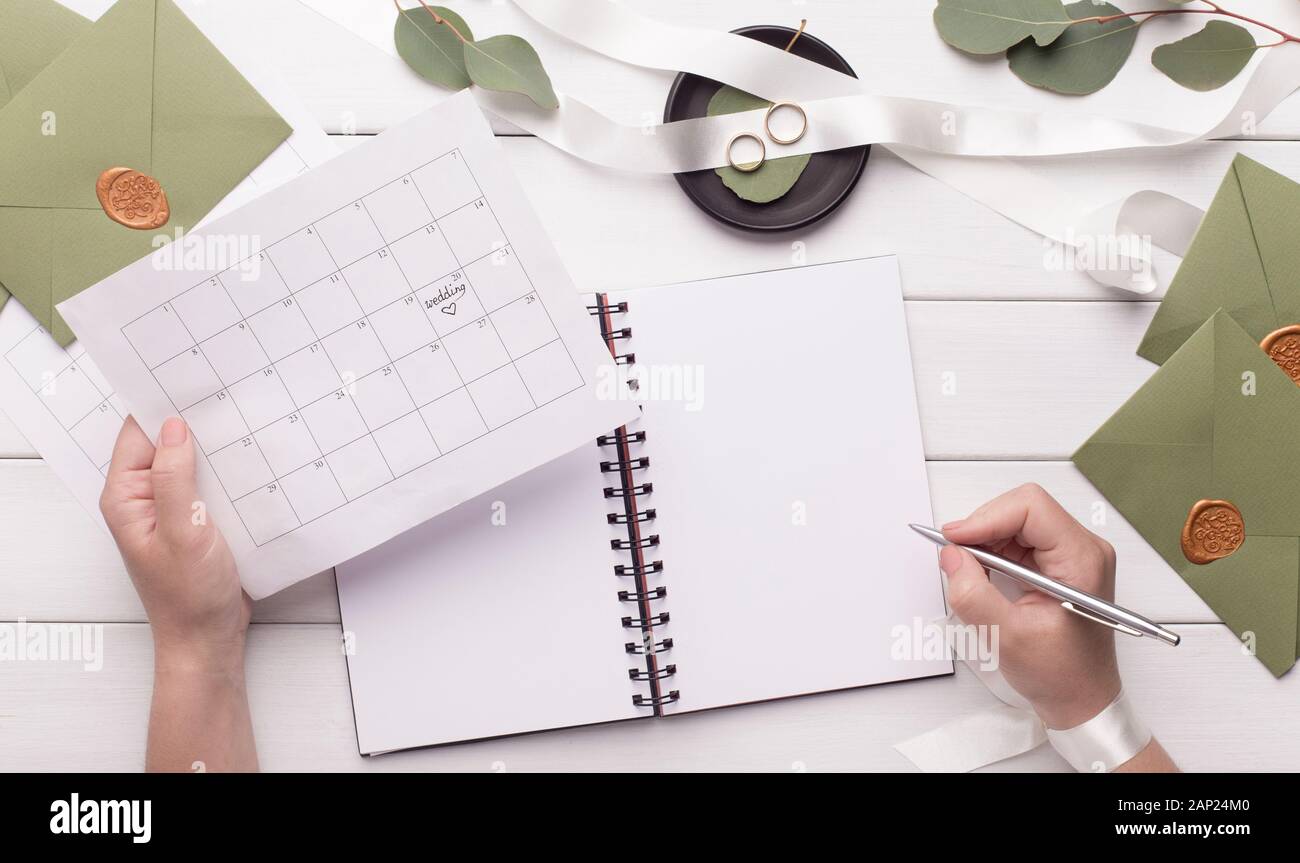 Female choosing marriage date, filling in planners on white Stock Photo ...