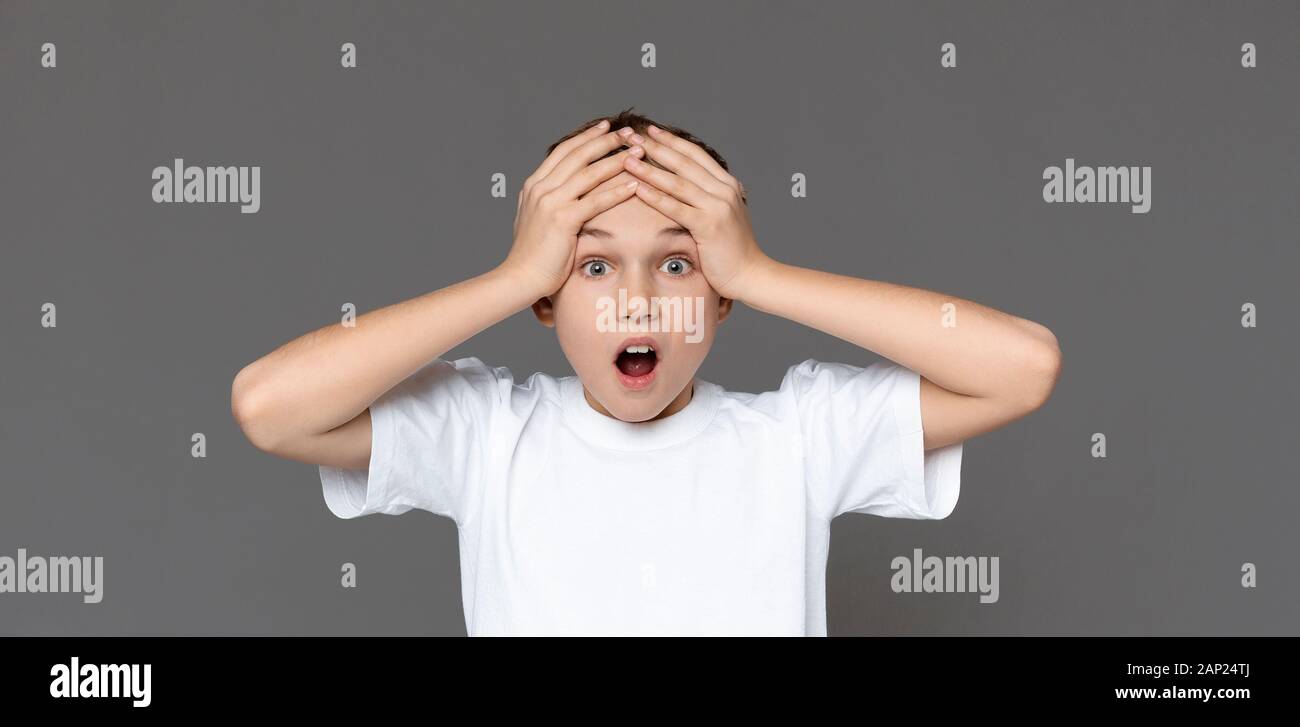 Amazed teenager screaming, holding head, grey background Stock Photo ...