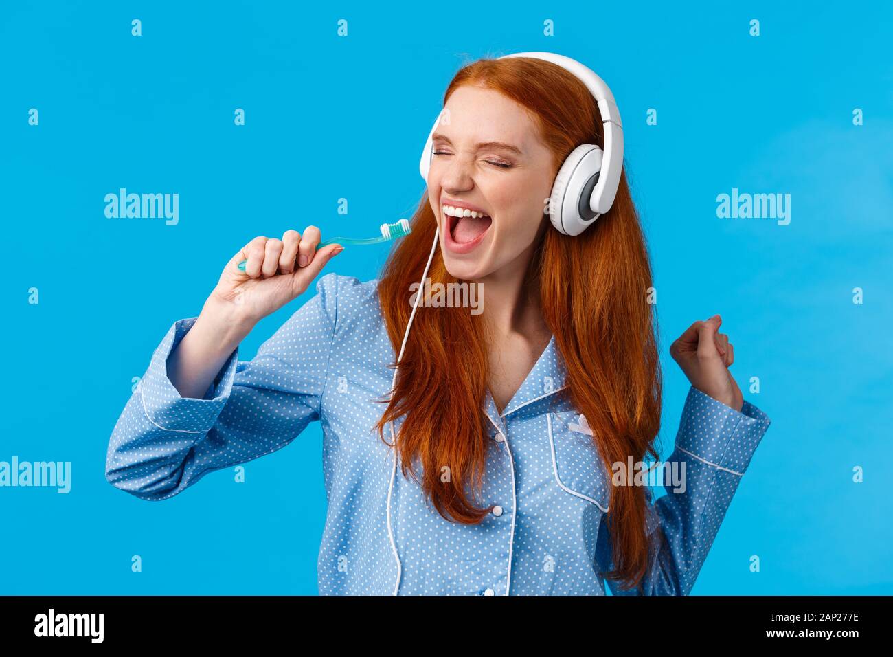 Sing like no one seeing. Carefree and excited joyful redhead female in ...