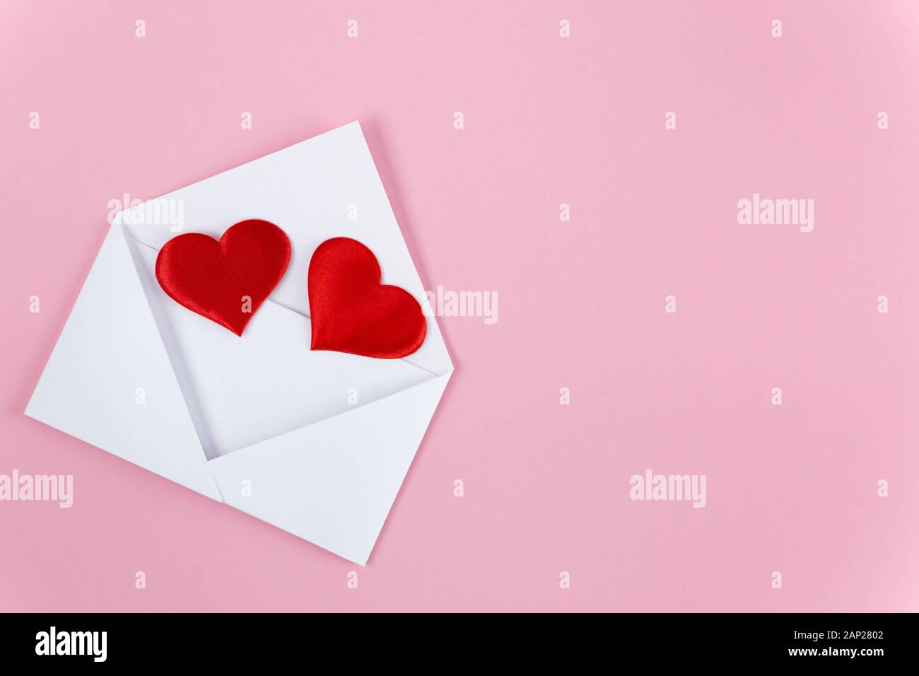 red hearts spill out of a white envelope on a pink background Stock ...