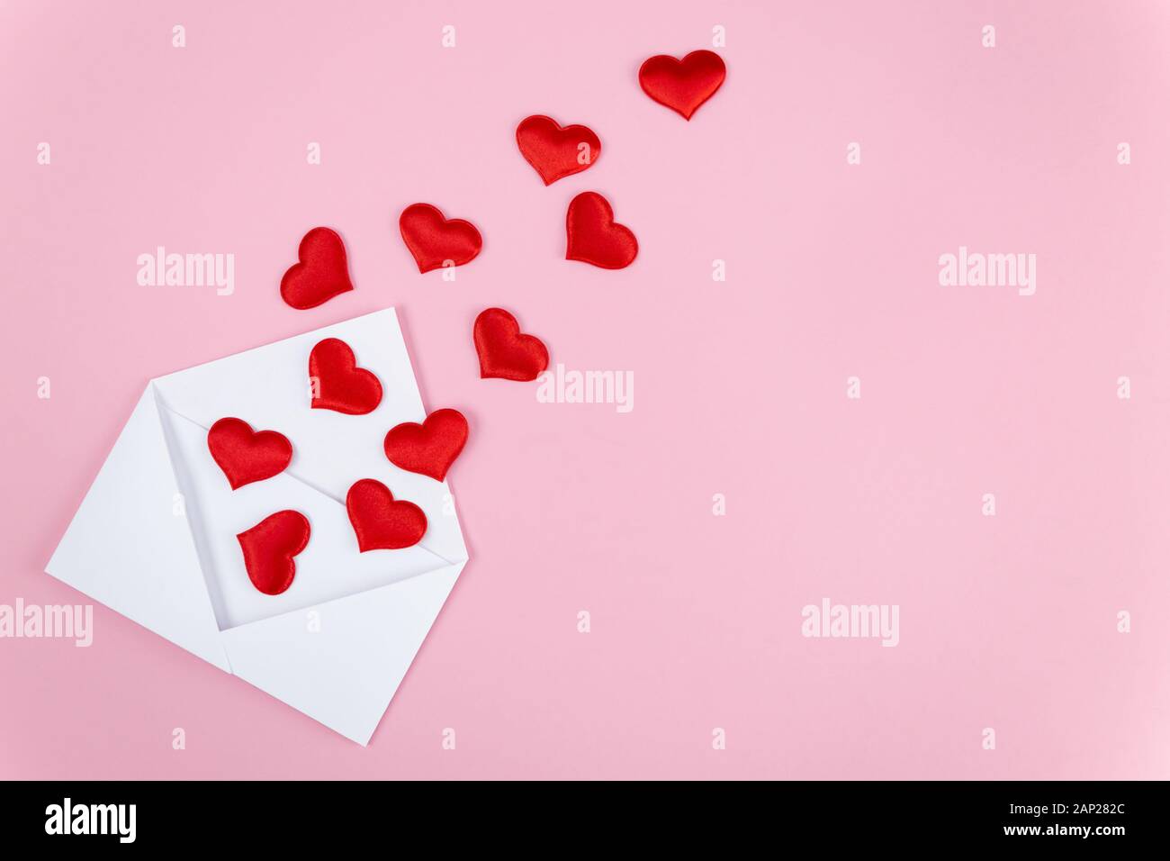 red hearts spill out of a white envelope on a pink background Stock ...