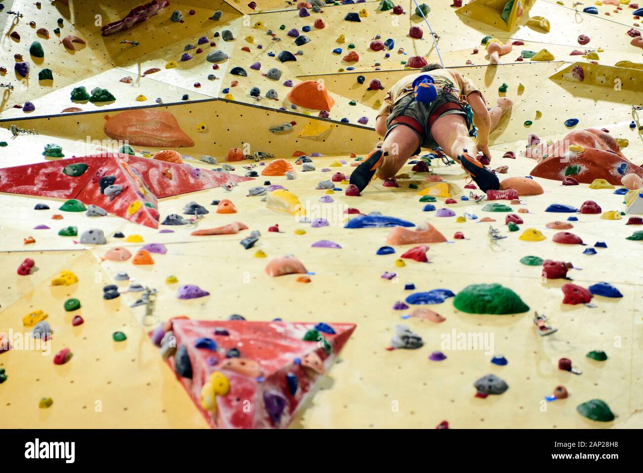Man climbing wall in bouldering gym. Detail on legs and equipment Stock ...