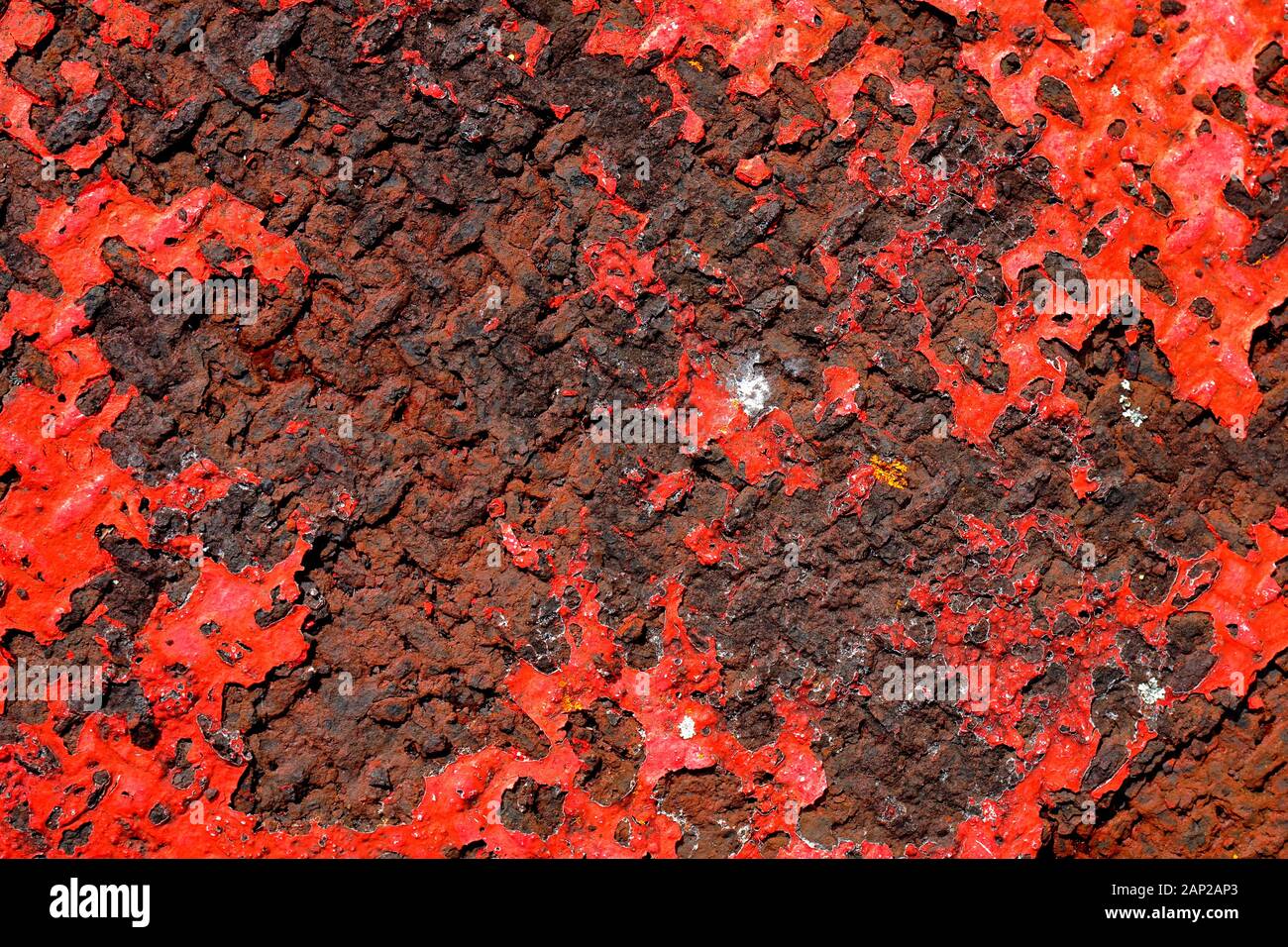 Old red paint flaking off rusting steel plate with lichen taking hold ...