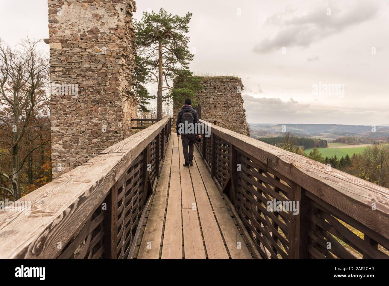Man tourist photographer holding camera walking on old wooden bridge in ...
