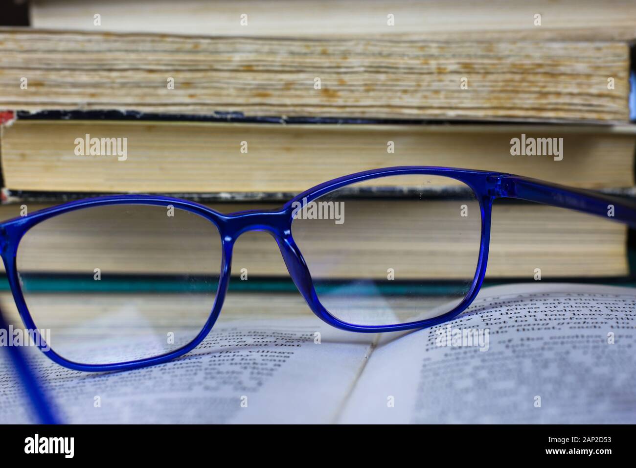 View on old open yellowed book with blue reading glasses on antique ...