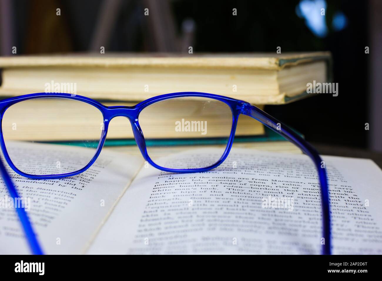 View on old open yellowed book with blue reading glasses on antique ...