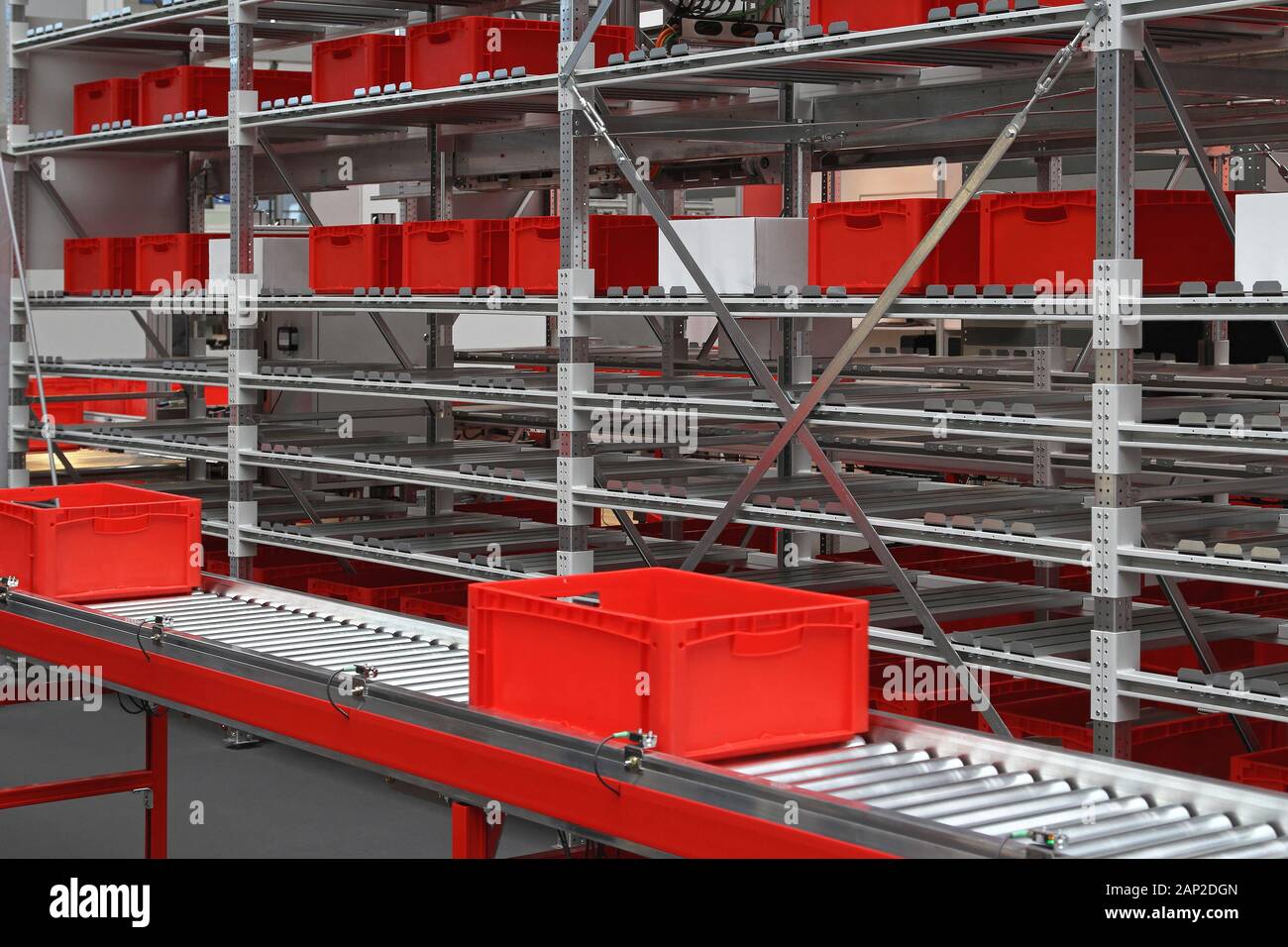 Red crates at conveyor rollers in distribution warehouse Stock Photo ...