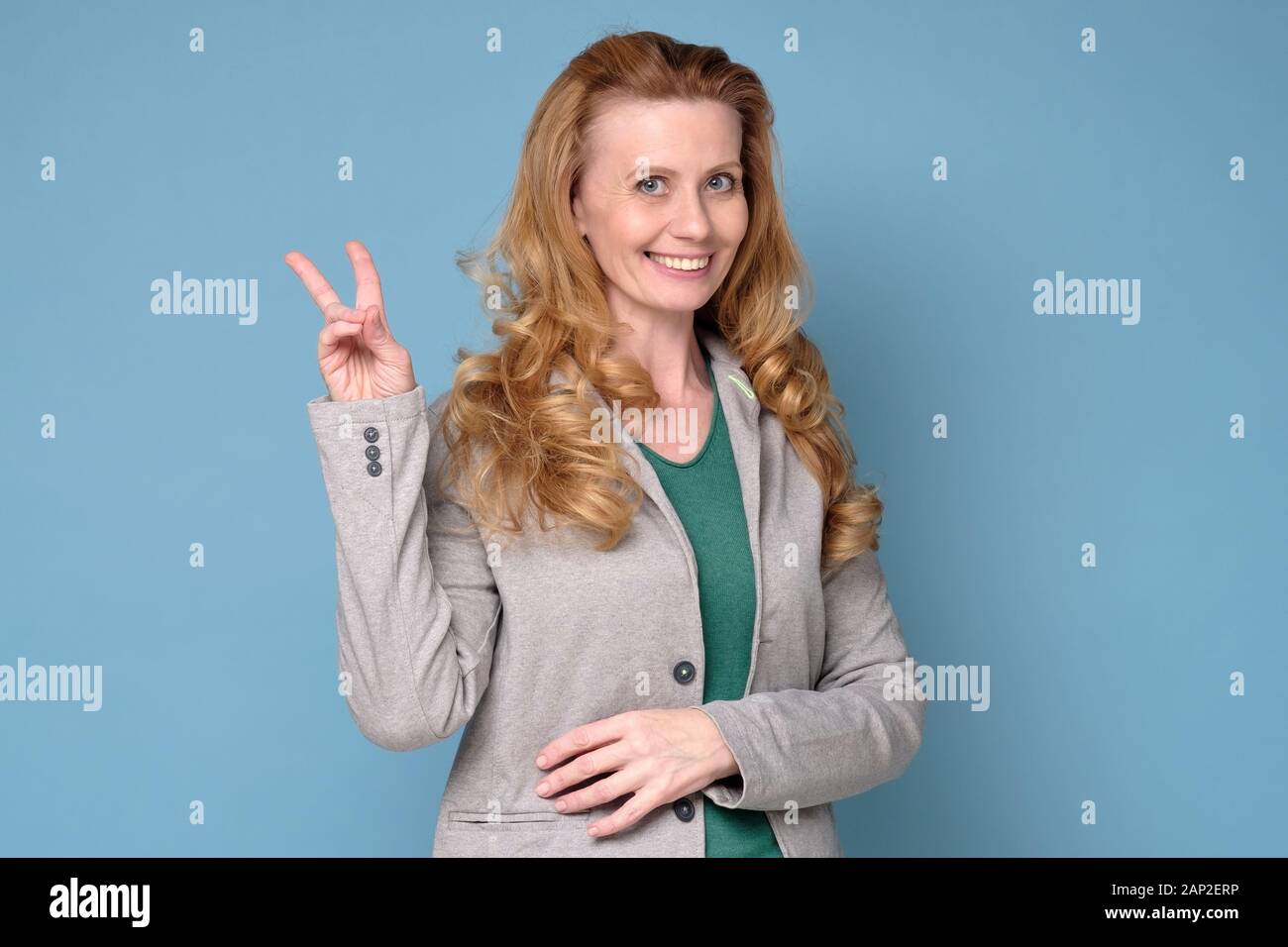 Mature caucasian happy woman giving peace showing two fingers sign ...