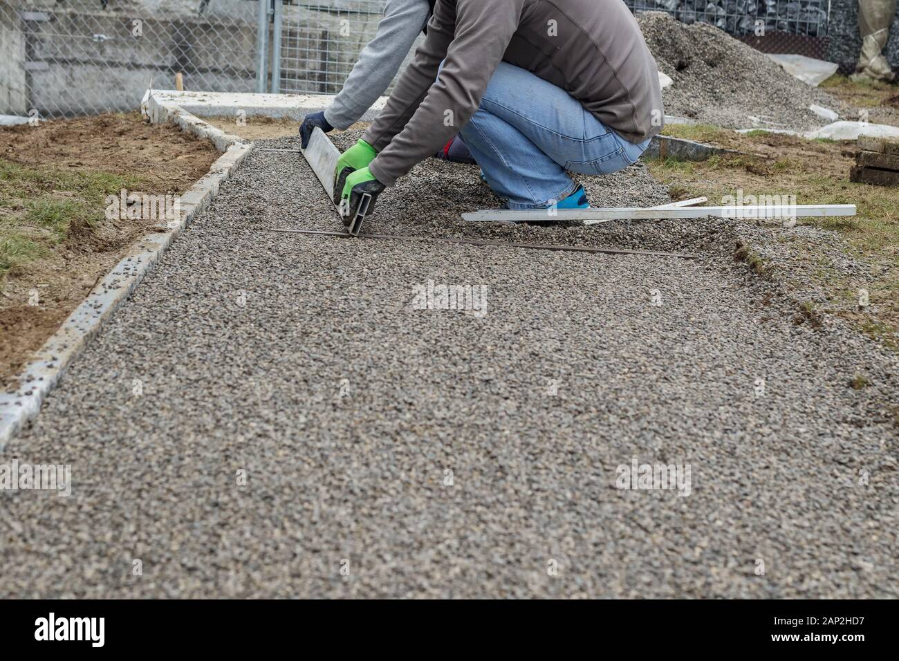 Worker leveling a metal screed board to gravel surface Stock Photo - Alamy