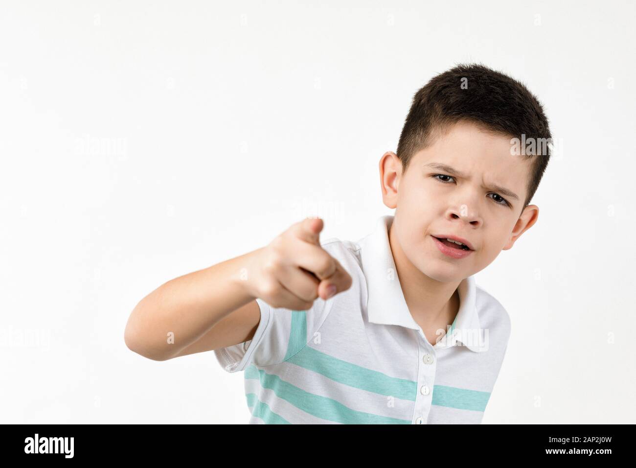 Cute little boy in striped t-shirt pointing camera on white background ...