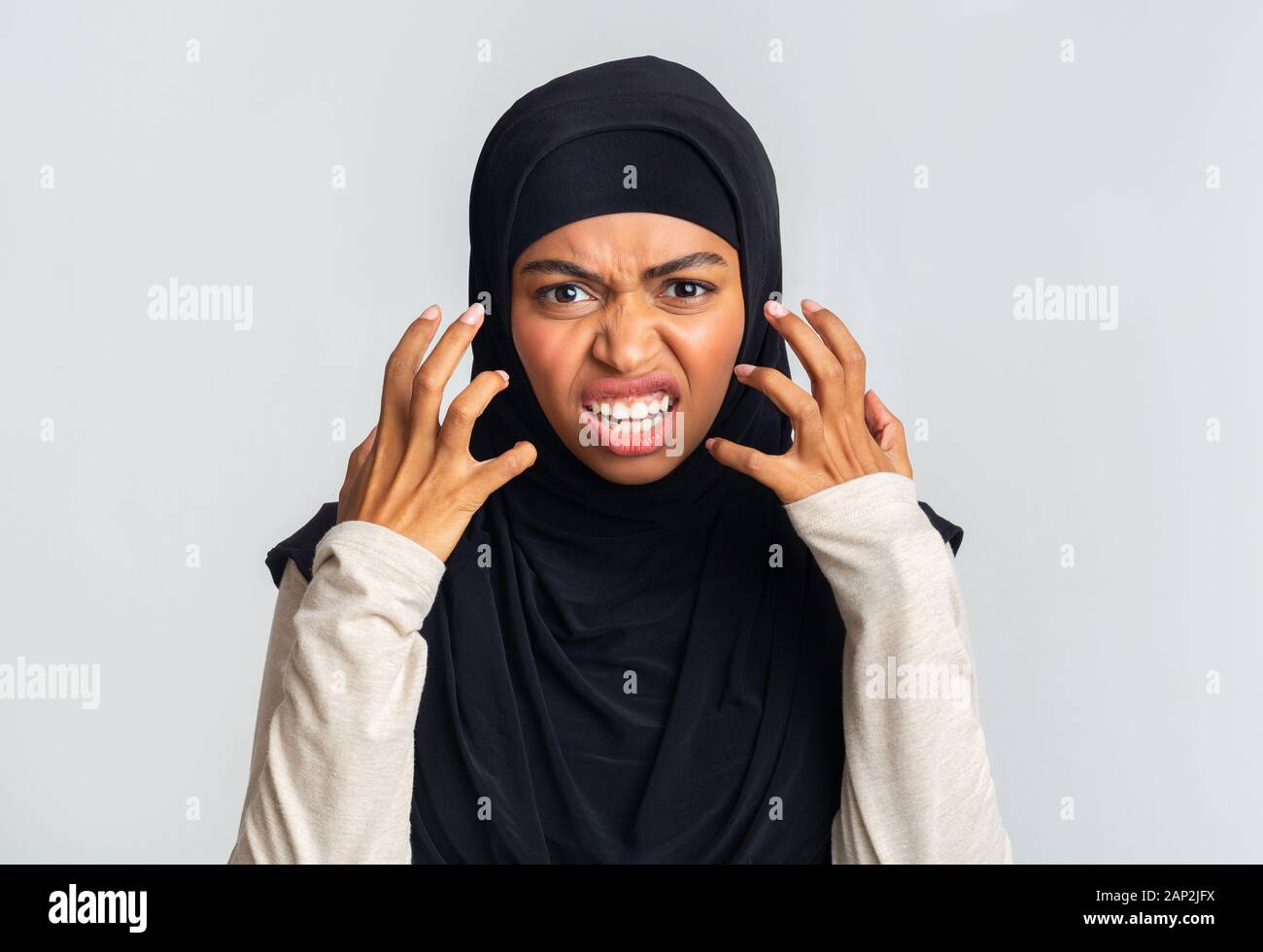 Angry muslim lady in hijab emotionally grimacing and gesturing in rage ...