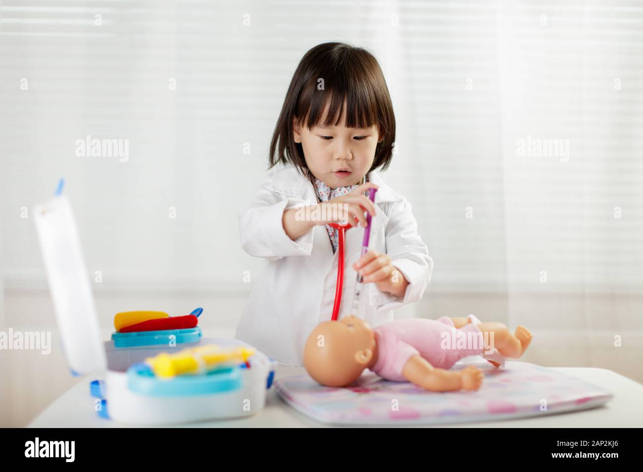 toddler girl pretend play doctor role at home against white background ...