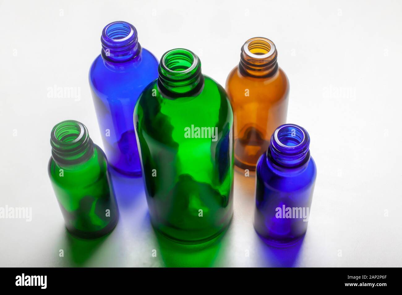 five small colored bottles on a white background with colored shadows ...