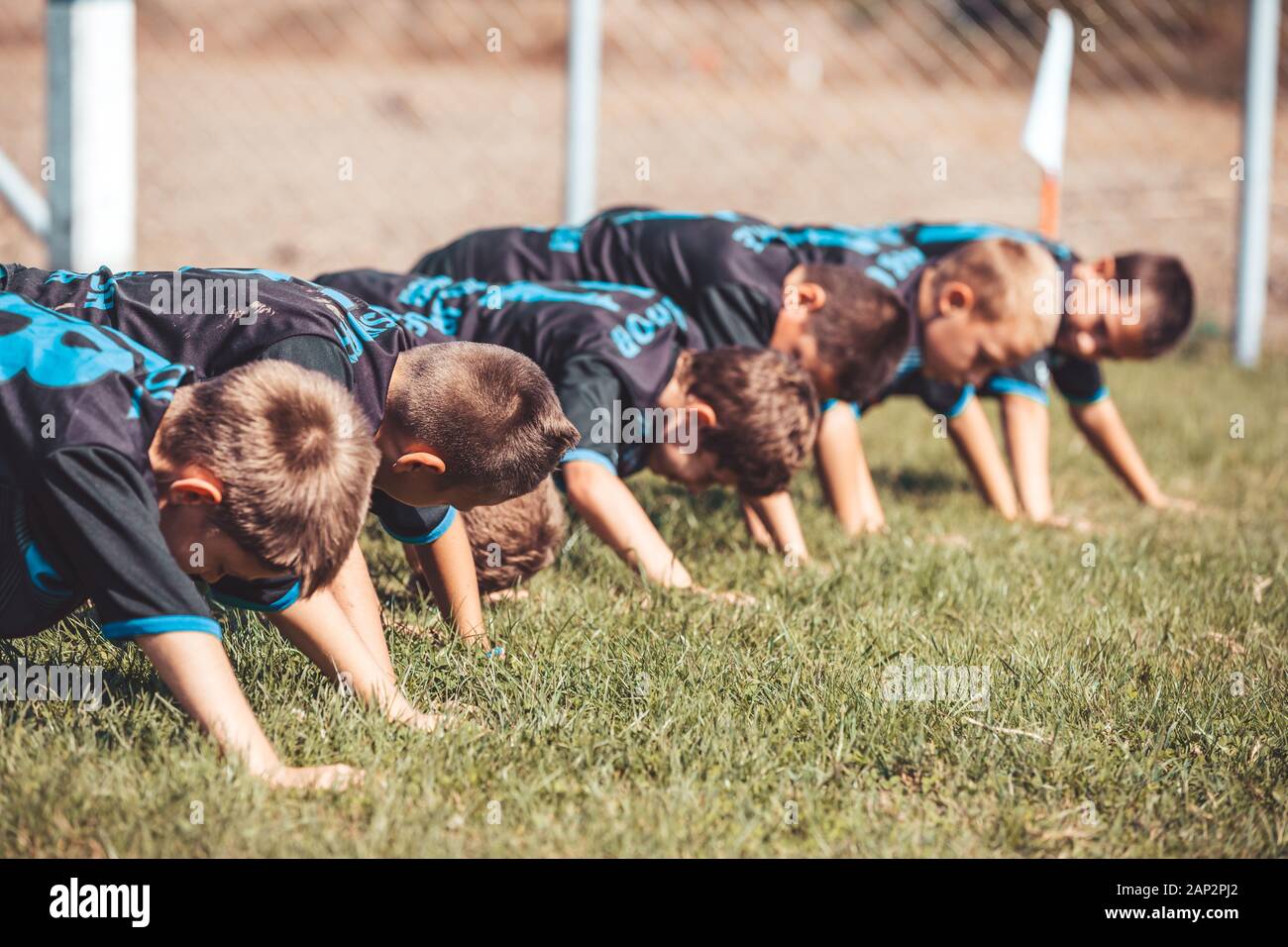 Group of young football players perform warm-up exercises before ...