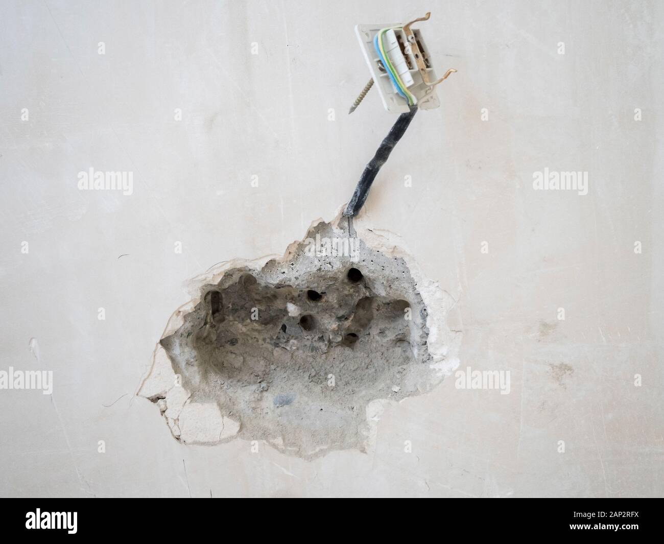 Hole in the wall under the socket Stock Photo - Alamy