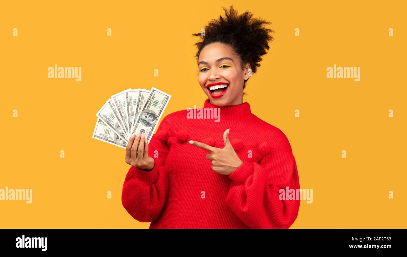 Happy black girl holding money at studio Stock Photo - Alamy
