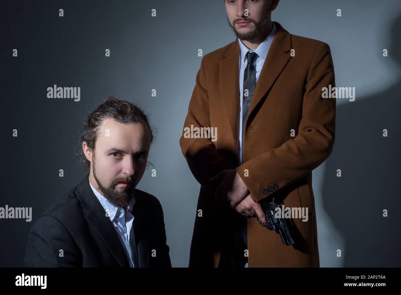 Portrait of two men in business suits, one of them is sitting, the ...