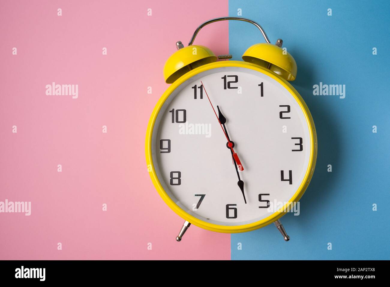 Yellow Retro style alarm clock on pink and blue background, flat lay ...