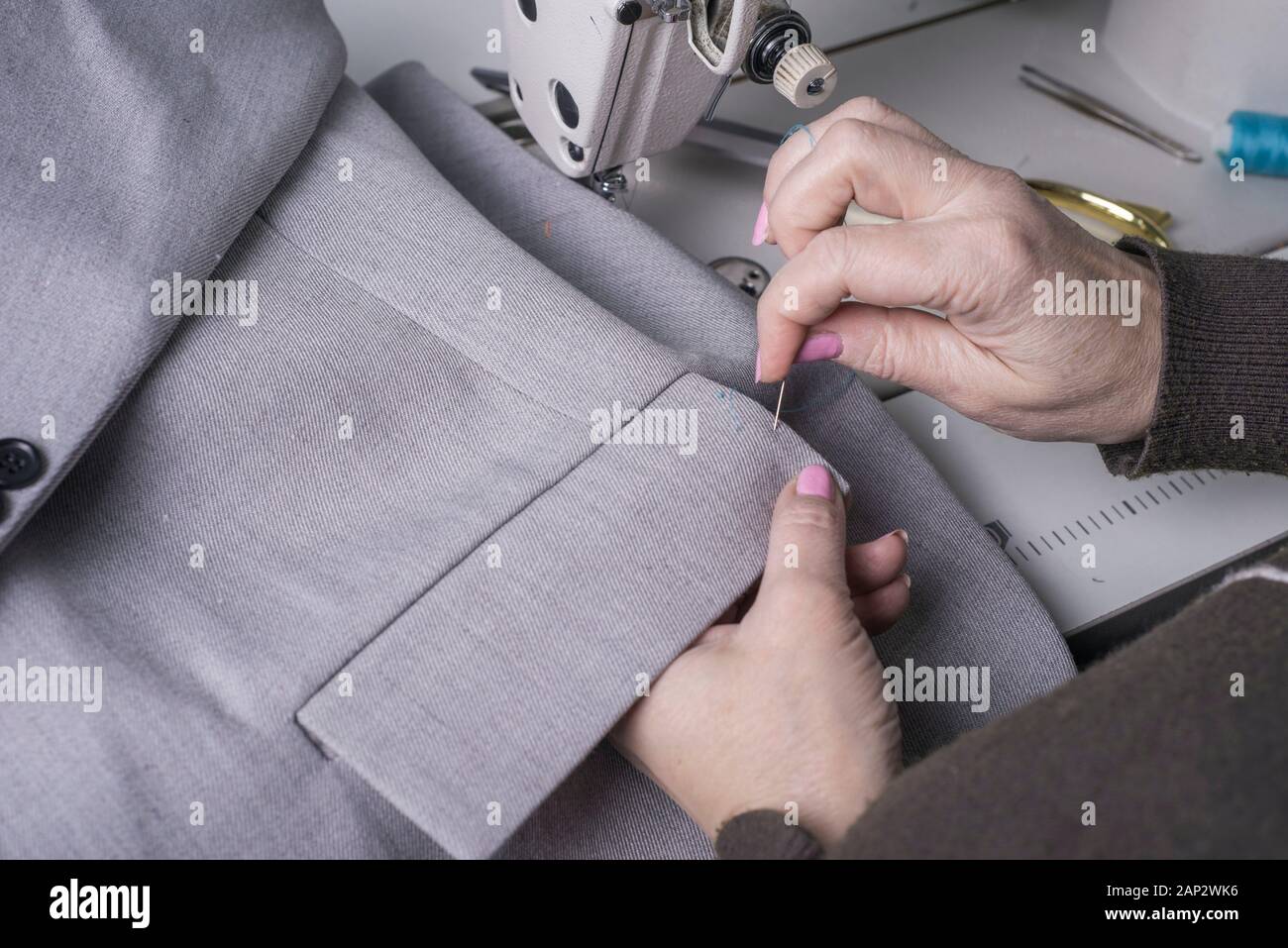 a couturier master, against the background of a sewing machine, sews ...