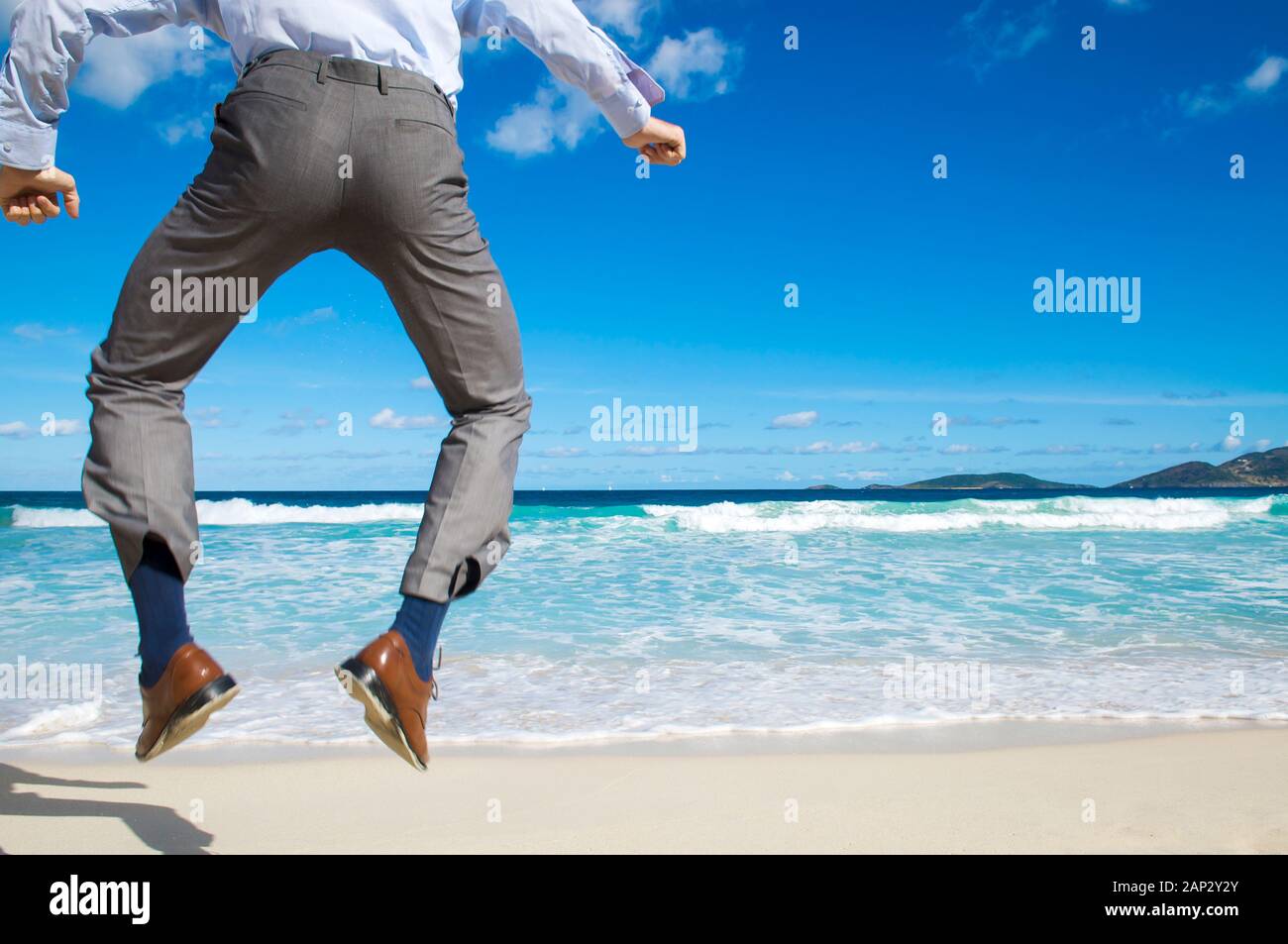 Unrecognizable businessman jumping into the air above a tropical beach ...