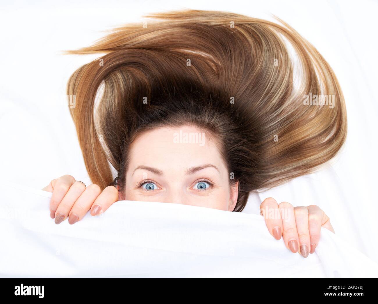 Amazing girl with open eyes looking out from under the covers Stock ...