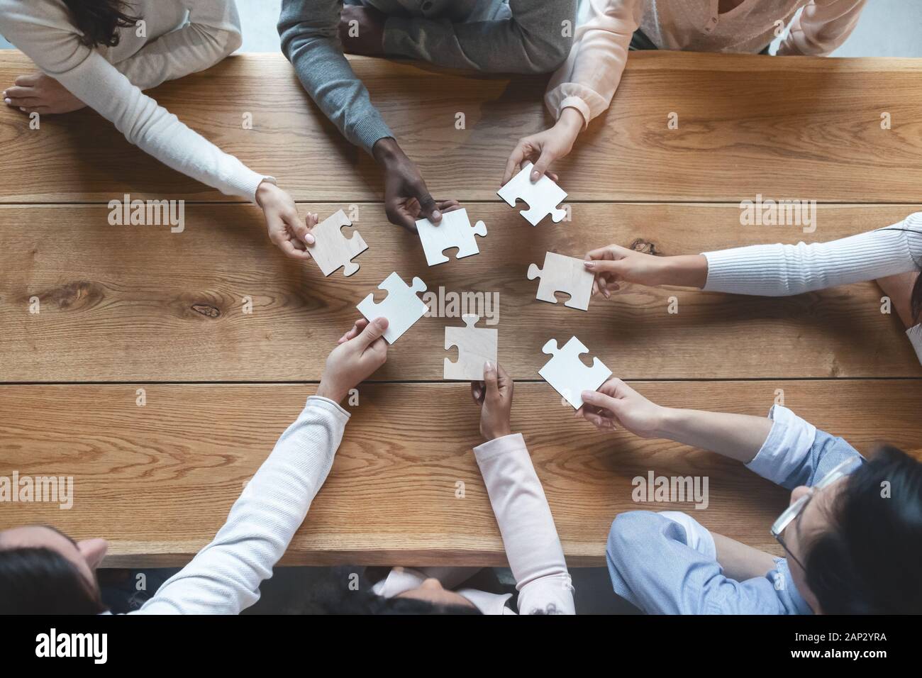 Creative team sitting at table and putting together puzzle pieces Stock ...