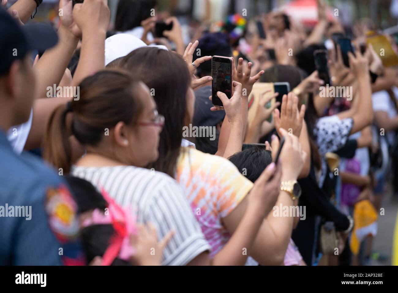 People within a large crowd taking photographs or video with their ...