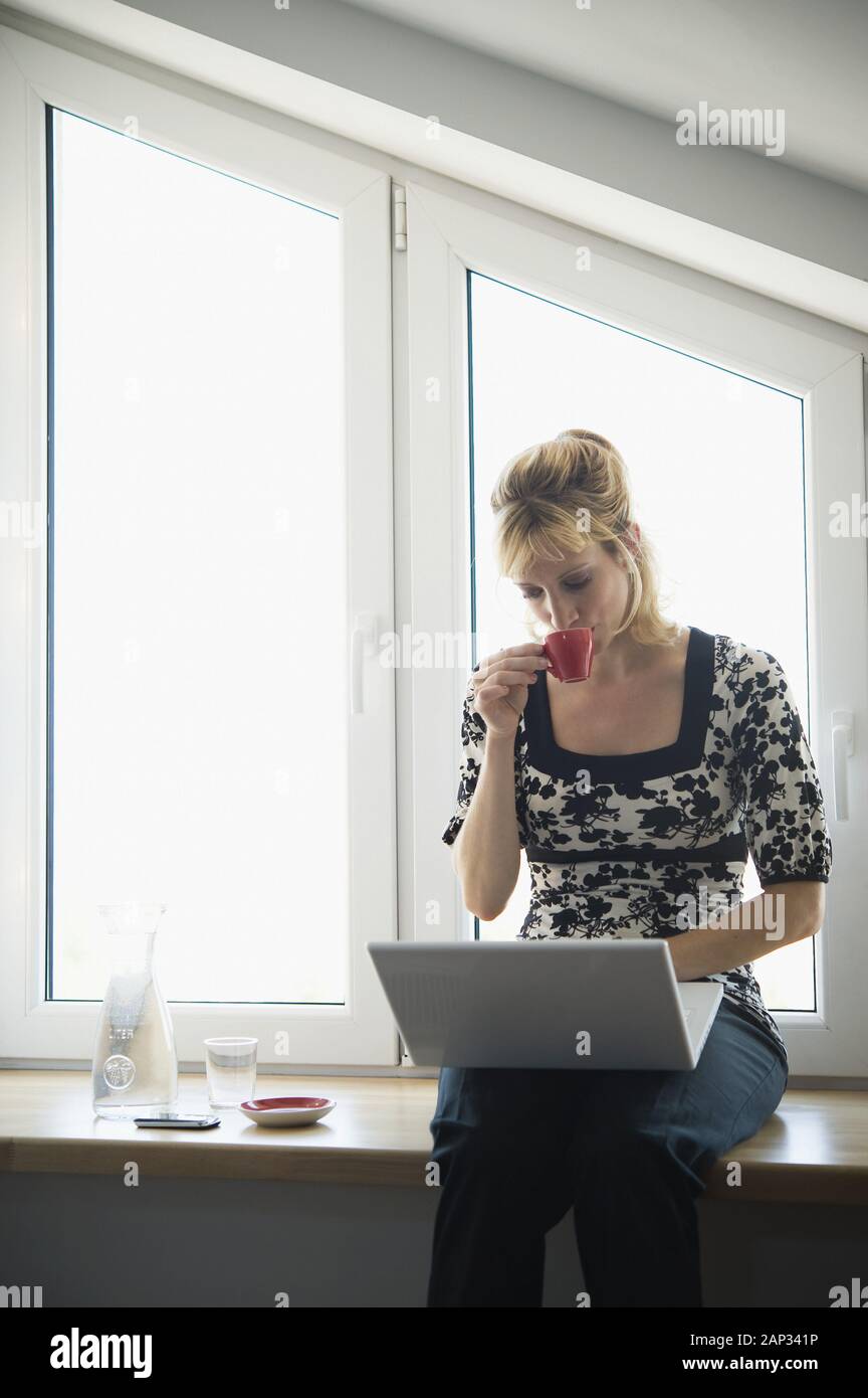 Junge Frau mit Laptop am Fenster - Young Woman with Computer at the ...