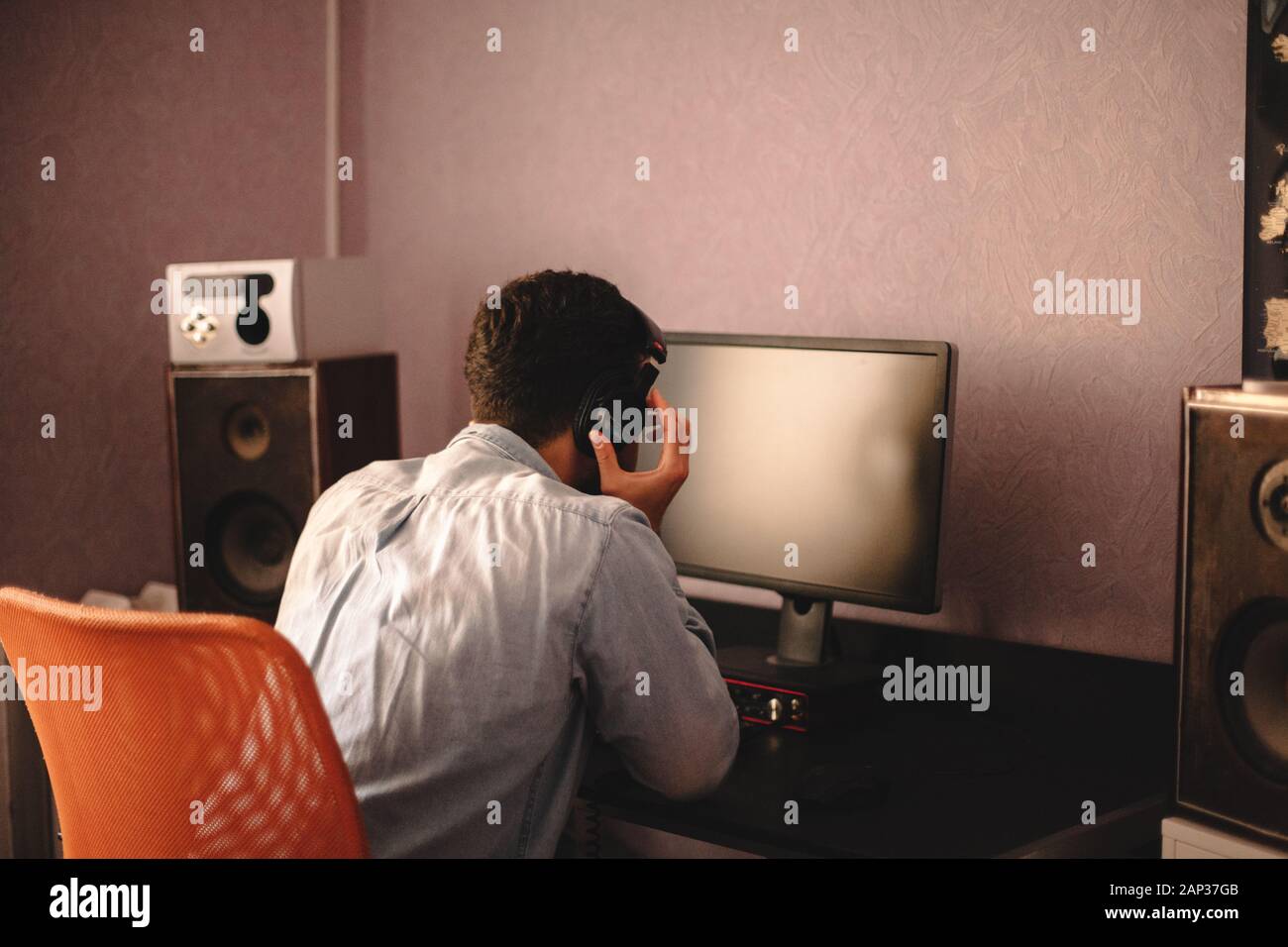 Concentrated man listening music on headphones sitting by computer ...