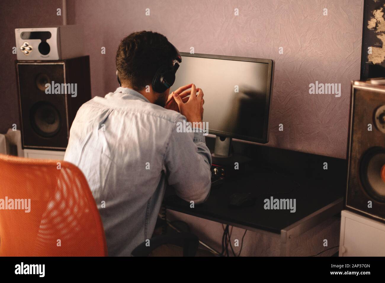 Concentrated man listening music on headphones sitting by computer ...
