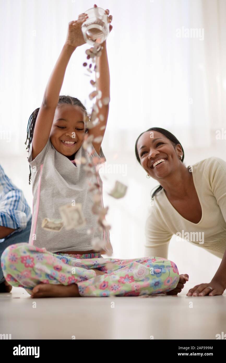 Girl pouring out money from jar Stock Photo - Alamy