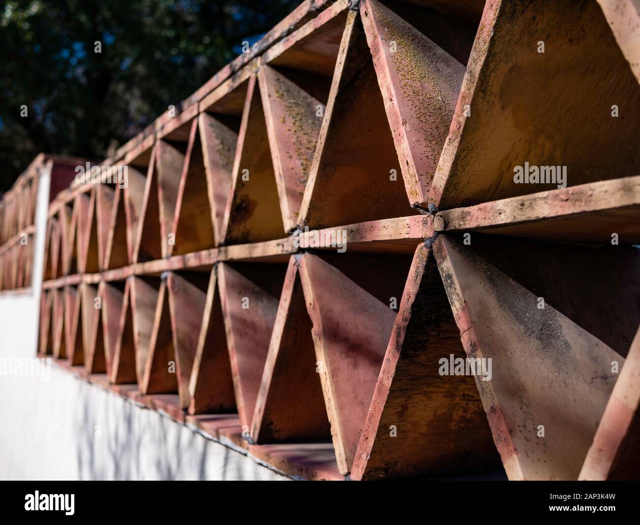 Pyramid shaped stone tiles create openings on top of urban fence Stock ...